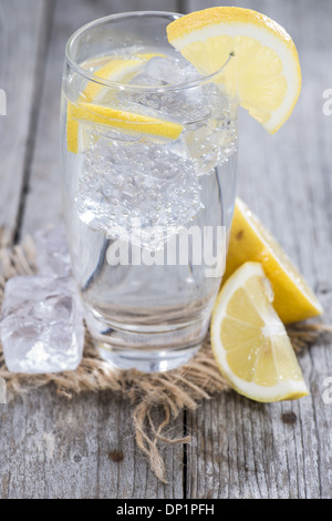 Fresh Lemon Sparkling Water with Ice on a rustic wooden board on a ...