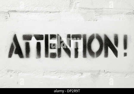 attention word textured stencil print on the white brick wall Stock ...