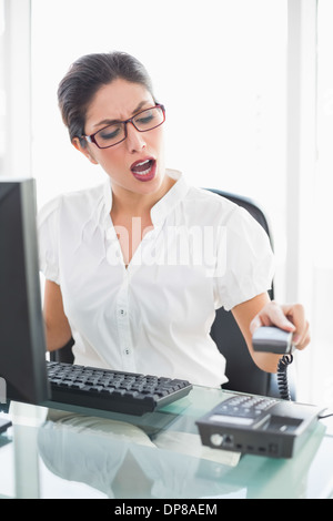 Angry businesswoman sitting at desk hanging up phone Stock Photo - Alamy