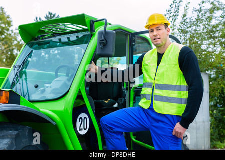 Builder or driver standing in front of construction machinery on ...