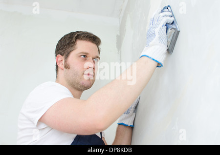 Male plasterer in uniform polishing the wall Stock Photo - Alamy