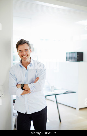 Portrait of smiling man standing in station with suitcase and smart ...