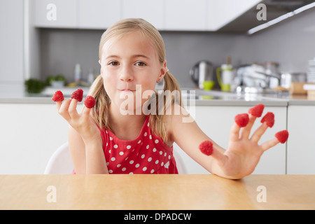 Girl eating raspberries from fingers Stock Photo - Alamy