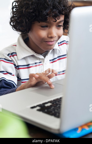Smiling boy using laptop at home by wall Stock Photo - Alamy
