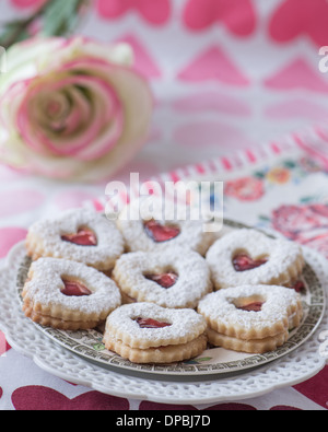 Plate with heart shaped cookie and rose flowers on light background ...