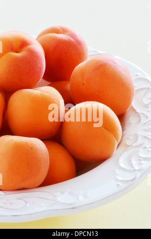 Fresh ripe apricots in a bowl and a knife on white background with ...