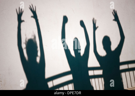 Creative photo of happy people shadows on white wall gesturing high ...