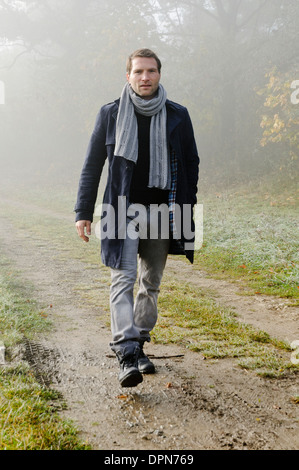 A young man walks along a dirt road in the forest, mountains Stock ...