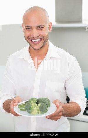 Young bald man eating fresh and healthy fruits pointing thumb up to the ...