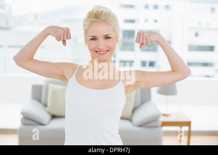 Fit woman in sportswear flexing muscles in fitness studio Stock Photo ...
