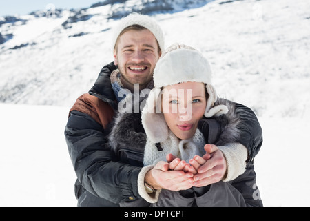 Couple with cupped hands on snow covered landscape Stock Photo - Alamy