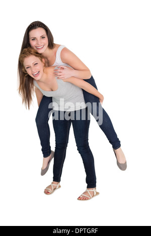 Full length of a young female piggybacking friend Stock Photo - Alamy