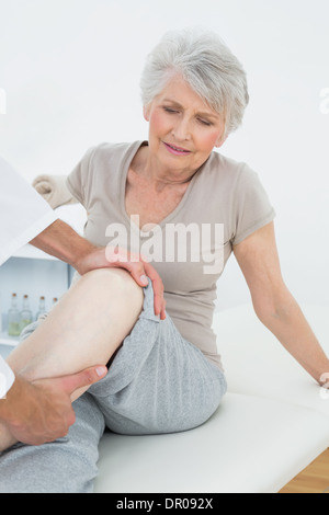 Female Physiotherapist Getting Senior Woman To Squeeze Rubber Ball At ...