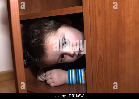 Scared child boy hiding in wardrobe Stock Photo - Alamy