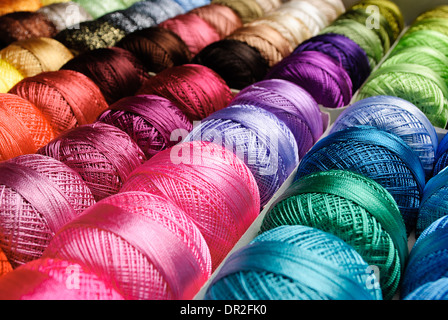 Different color threads on rows in the store Stock Photo - Alamy