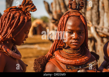 Two women of the Himba tribe face each other in traditional dress and ...