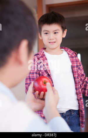 Son giving apple to father Stock Photo - Alamy