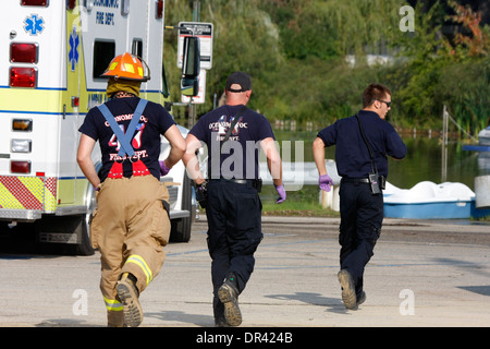 Emergency Medical Technicians EMTs and firefighters help a patient on a ...
