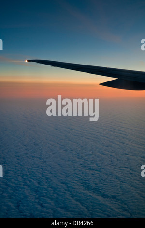 Airplane is flying over low clouds against mountains with snowy peaks ...