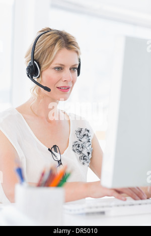 Call center. Beautiful young woman using headset and computer to help ...