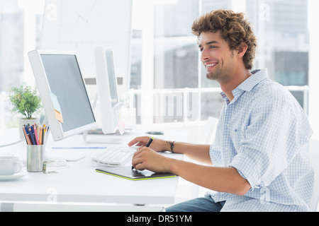 Happy young designer drawing on a graphics tablet with a stylus pen ...