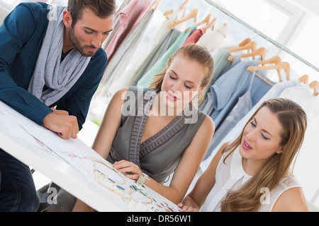 Three fashion designers discussing designs in a studio Stock Photo - Alamy