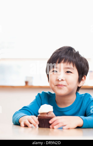 cute smiling boy eating cupcake with candle at birthday party Stock ...