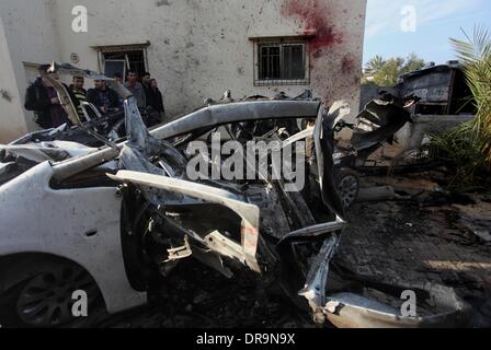 Palestinians gather around a car hit in an Israeli strike in Gaza City ...