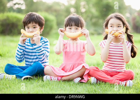 kids sitting on the grass eating bananas Stock Photo - Alamy