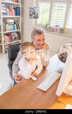 boy operating a computer using mouse and keyboard, He is looking at the ...