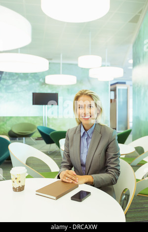 Young businesswoman sitting at table in front of computer monitor and ...