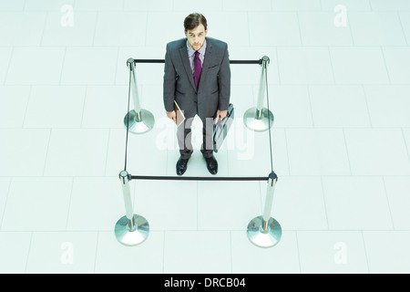 Businessman standing inside roped off area in lobby Stock Photo - Alamy