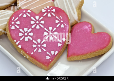 Heart shaped cookies on the pink plate on white wooden background. Flat ...