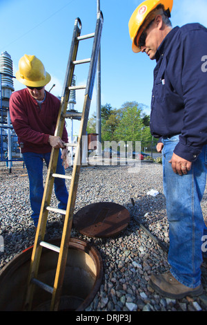Power engineers looking inside manhole at high voltage power ...