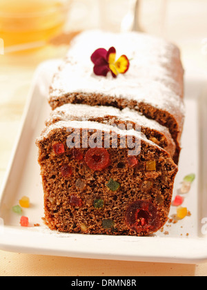 slices of biscuit plum cake on a white wooden board and fresh fruits ...