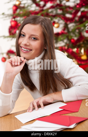 Happy young woman writing wish list dream notes for Christmas holiday ...