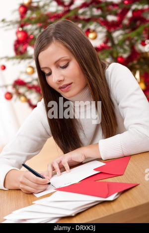 Happy young woman writing wish list dream notes for Christmas holiday ...