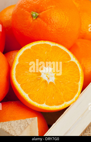 Oranges in wooden fruit crate and a knife on a black kitchen towel and ...