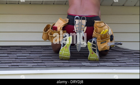 A single construction worker instalating house roof rain gutter a belt ...