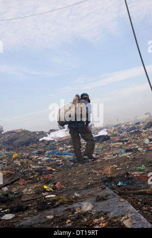 A scavenger man is carrying a sack while collecting recyclable material ...