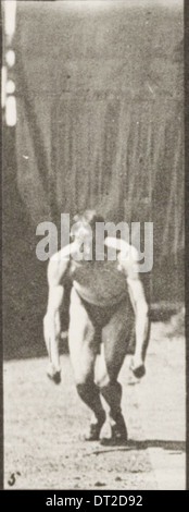 A man in a pelvis cloth performing a standing broad jump, captured in ...