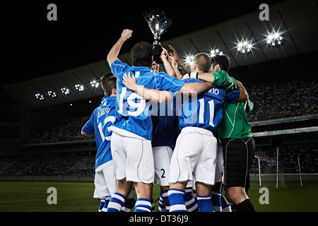 Football player holding up trophy, cheering, winner, winning, confetti ...