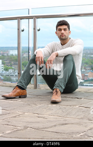 Handsome sexy topless male model relaxed sitting on the beach with the ...