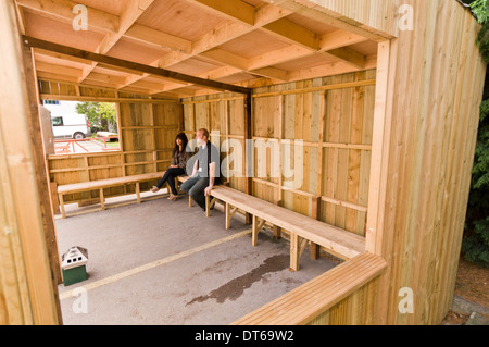 Man and a woman talking in a timber smokers shelter Stock Photo - Alamy