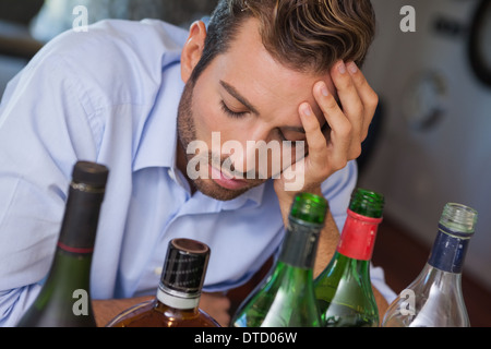 Drunk businessman looking at many spirit bottles Stock Photo - Alamy