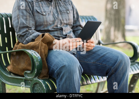 Midsection of university student using digital tablet at table while ...