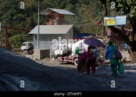 Nepalese women walking by a new cement plant, part of the construction ...
