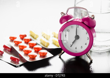 Medicine pills with red alarm clock on white background Stock Photo - Alamy