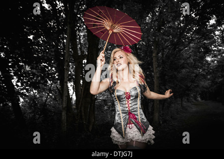 A woman wearing a laced basque, stockings and suspenders, holding an ...