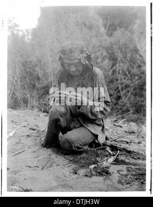 An elderly Havasupai Indian man is photographed crouching on the ground ...